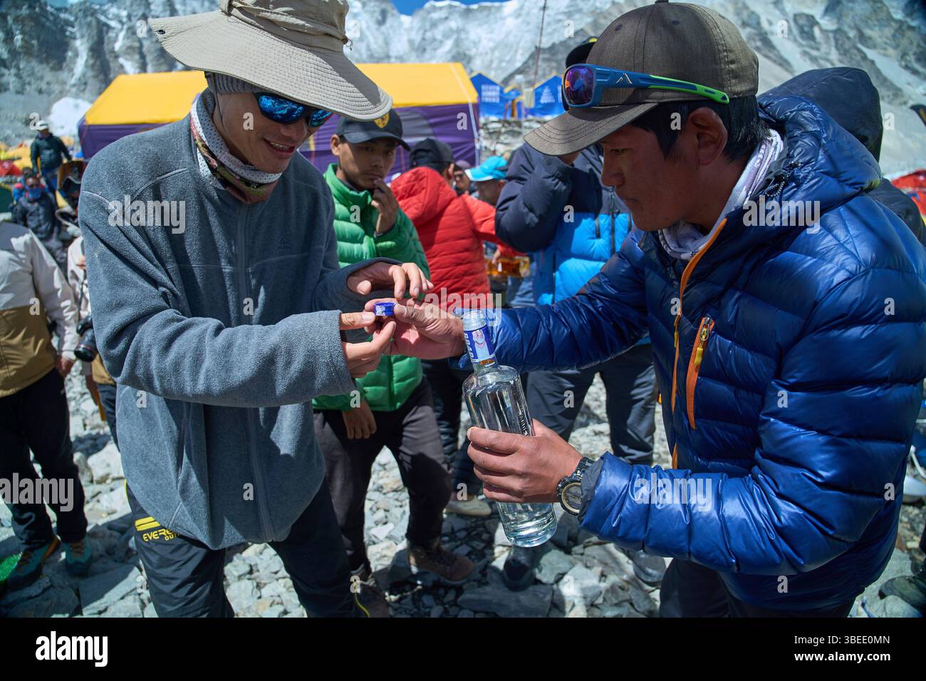A sherpa hands vodka, that was earlier offered to the Gods, to a ...