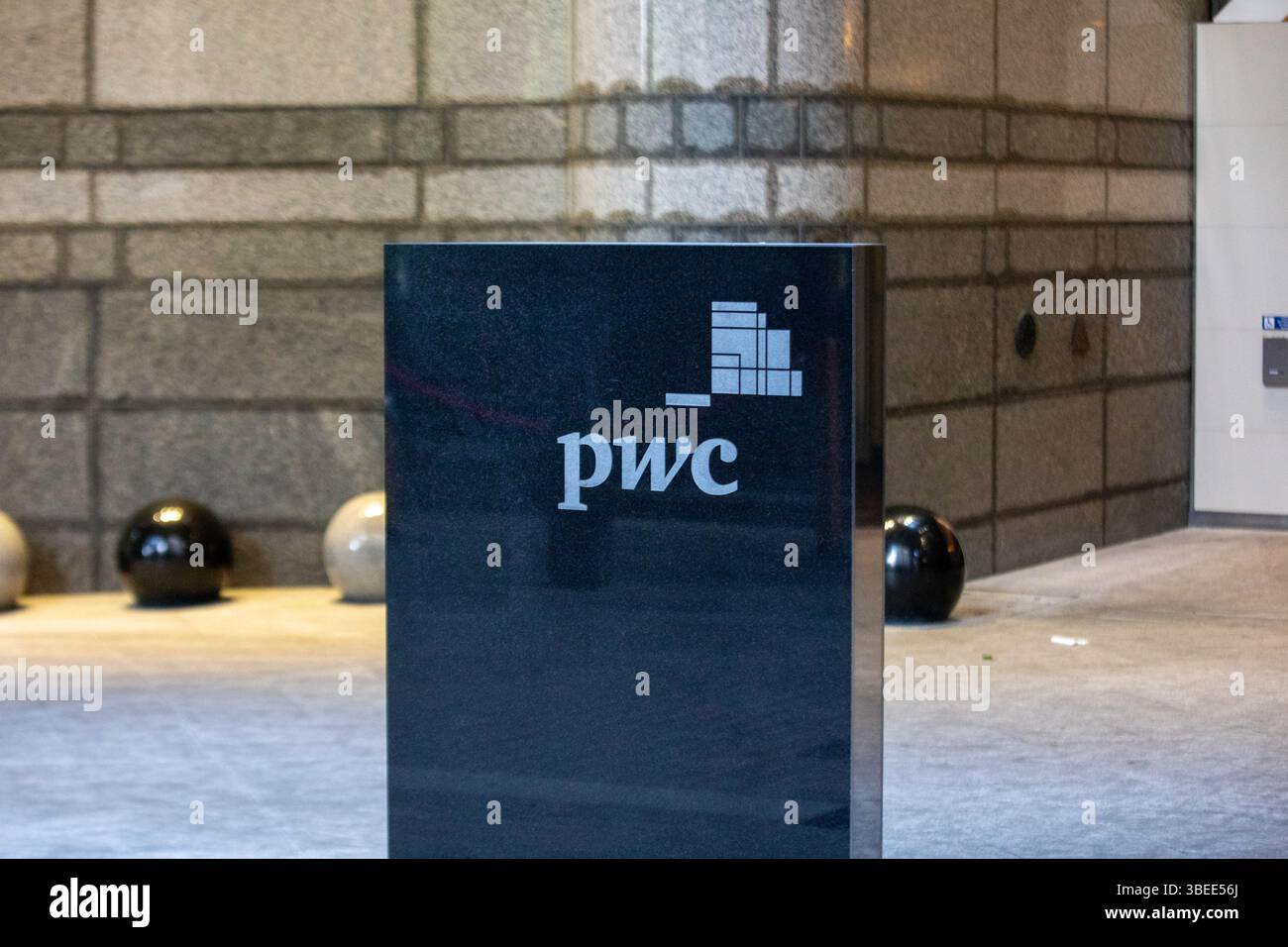 Close-up of a PwC sign at a building entrance in a London urban area ...