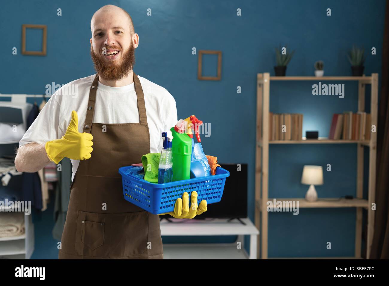 Handsome bearded bald man holding cleaning products and smiling ...