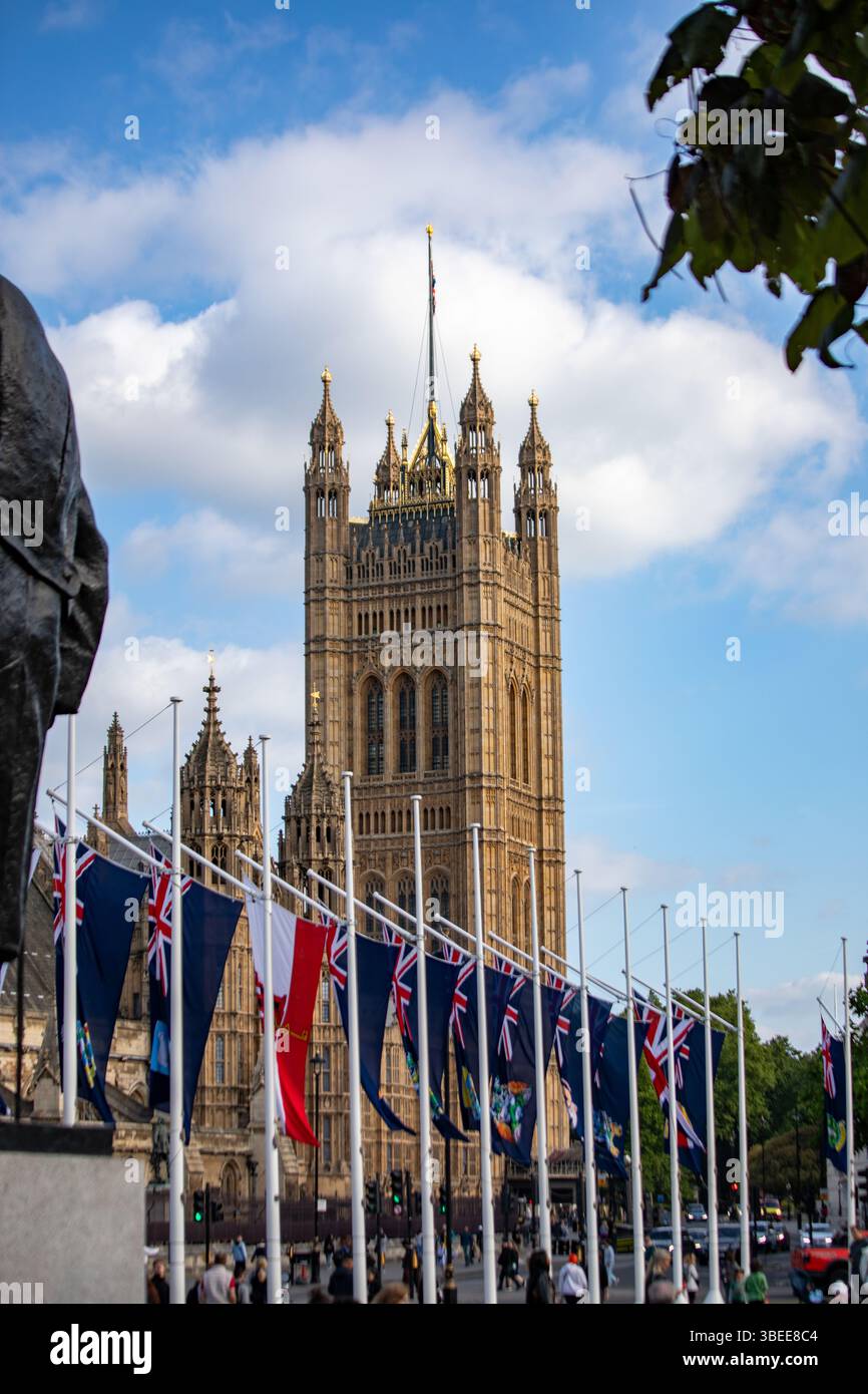 The iconic Houses of Parliament and Union flags in London, under a blue ...