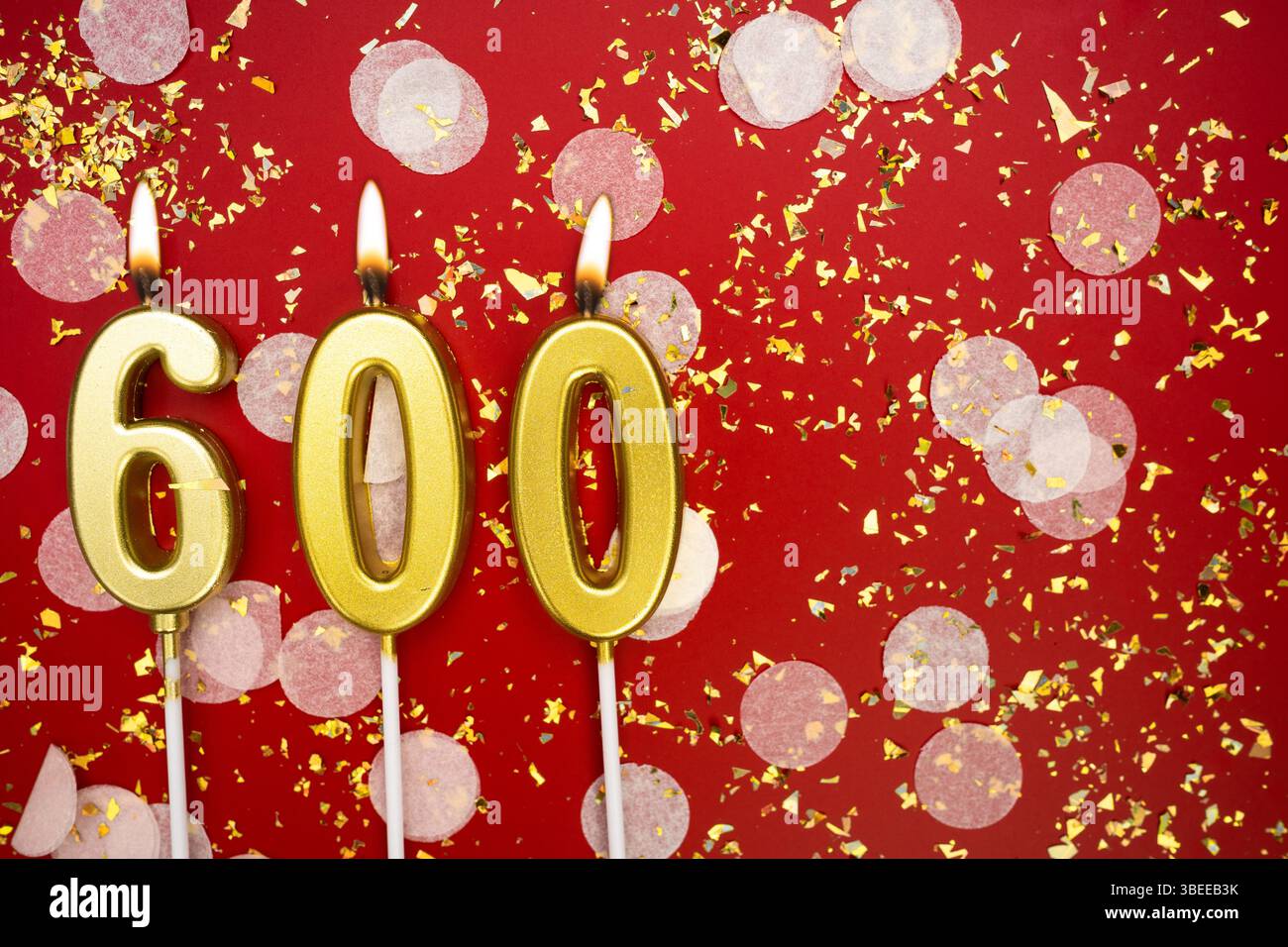 Burning Golden birthday candles on red confetti background, number 600 ...