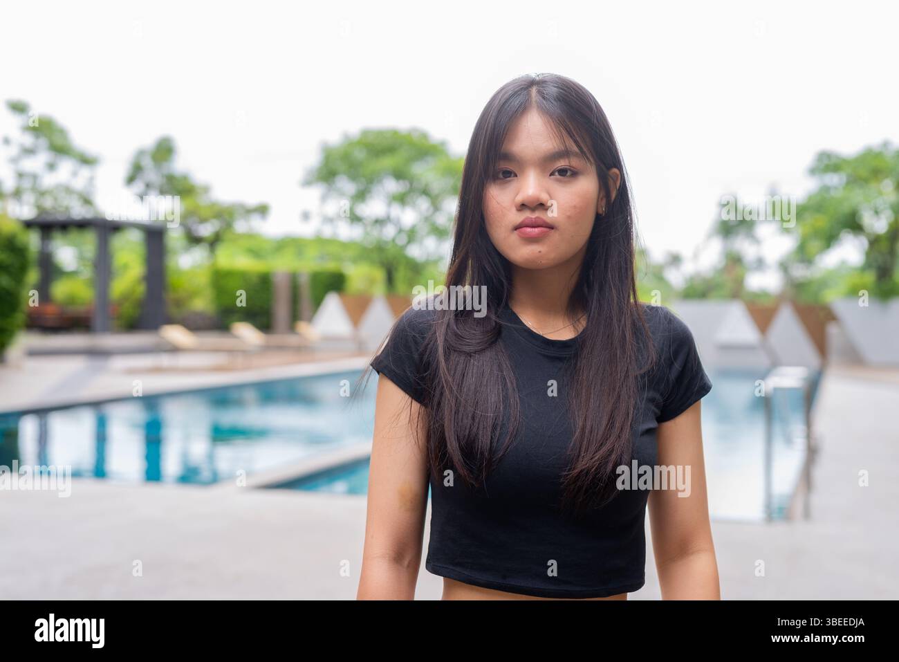 Young beautiful Asian woman relaxing next to swimming pool during ...