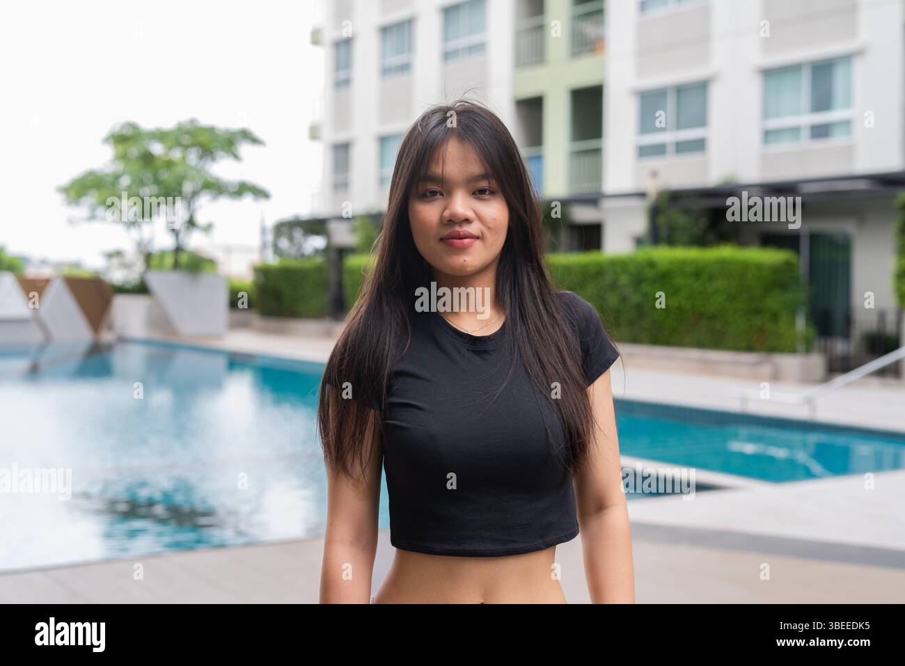 Young beautiful Asian woman relaxing next to swimming pool during ...