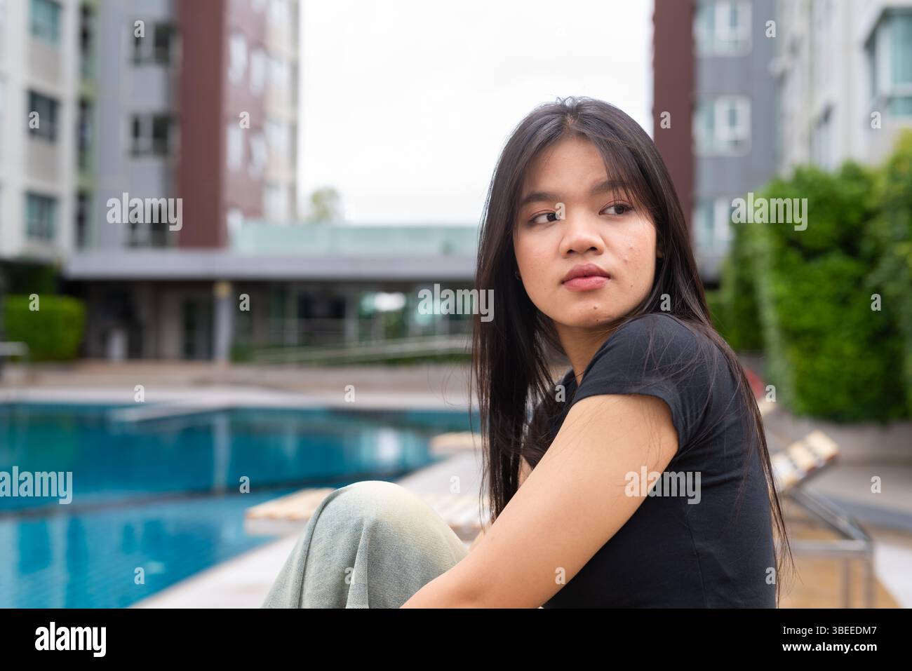 Young beautiful Asian woman relaxing next to swimming pool during ...