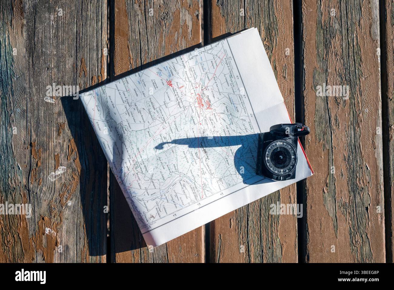 A detailed topographic map and a classic compass rest on an aged wooden ...