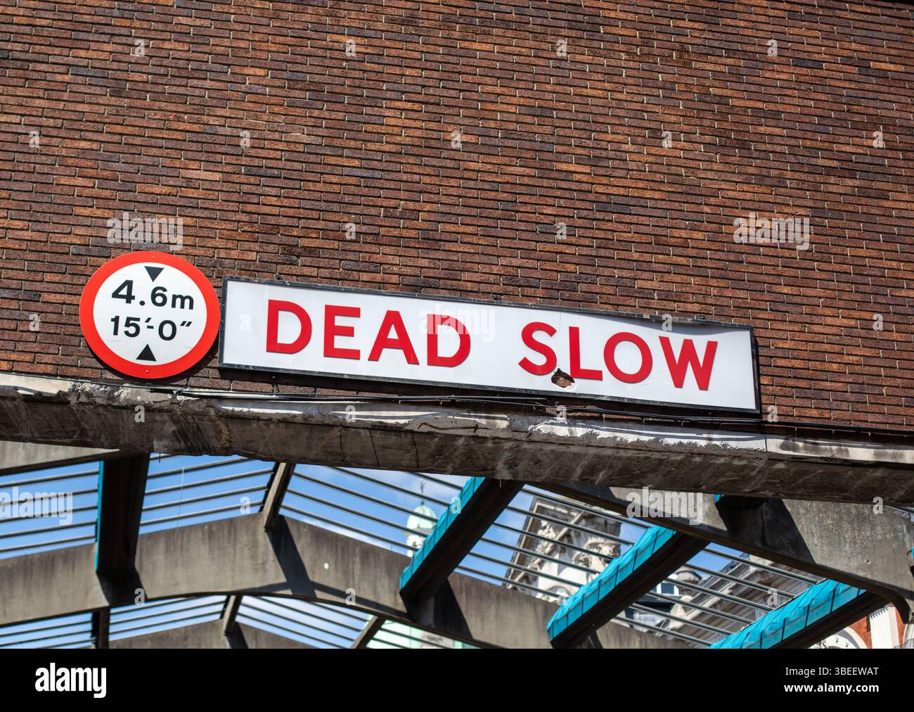 A cautionary Dead Slow sign on a brick wall in London, highlighting a ...
