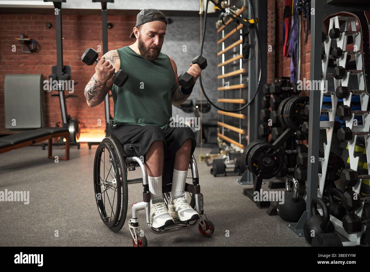 Person in wheelchair using dumbbells while exercising in modern gym ...