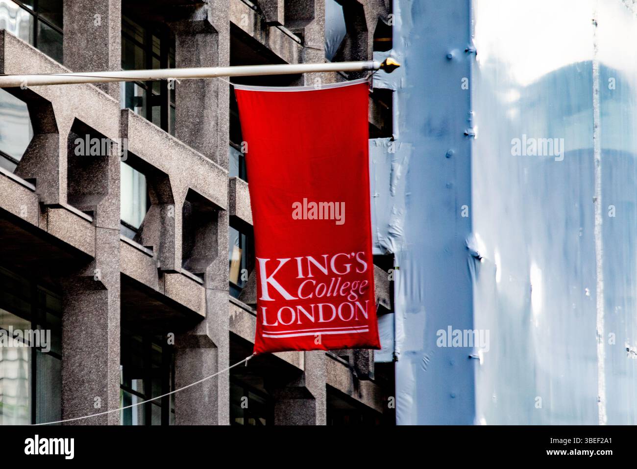 A red banner of Kings College London hangs on an urban building facade ...
