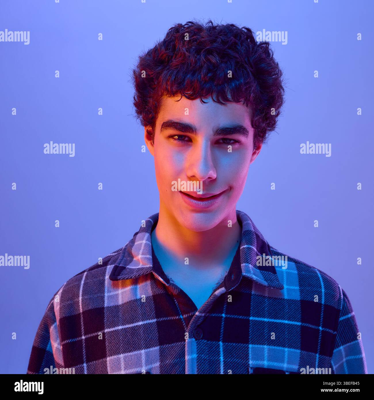 Close-up of teen boy smiling with raised eyebrow and relaxed expression ...