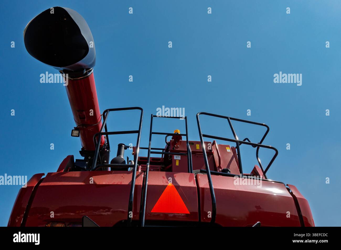 Rear view of a red agricultural combine harvester with grain auger ...