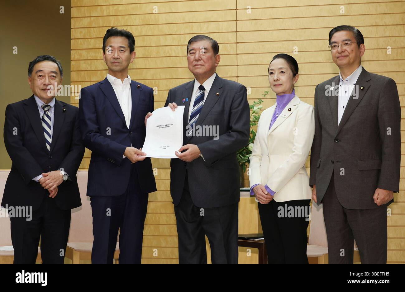 Japanese Prime Minister Shigeru Ishiba (C) receives a proposal for a ...