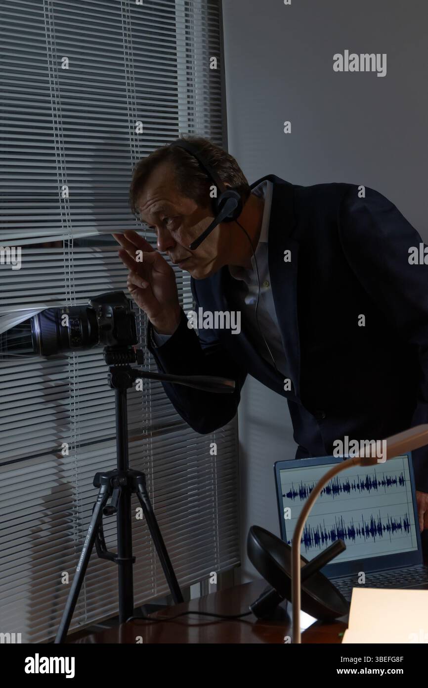 A spy with a headset and a camera peeks through the window for covert ...