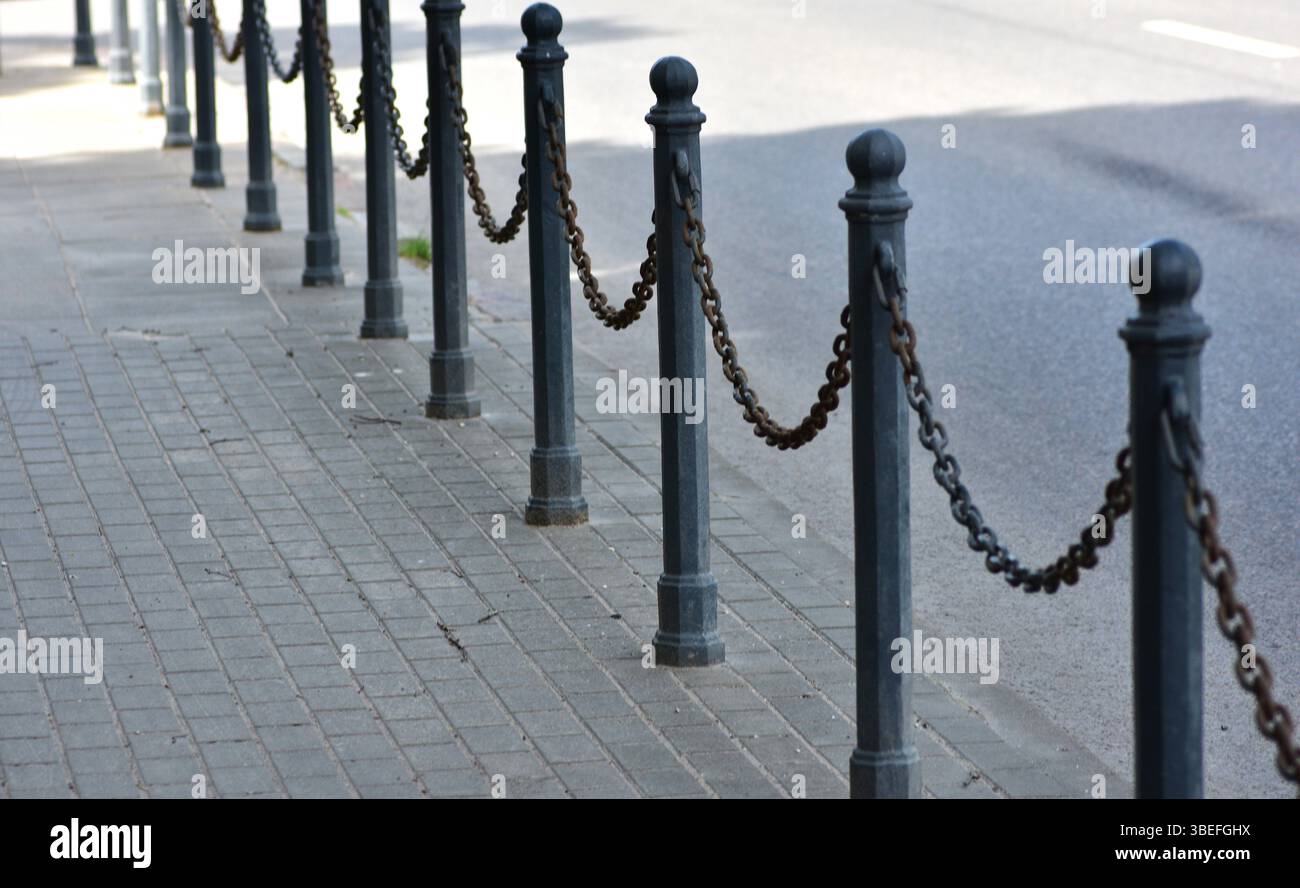 Iron posts with linked chains form a vintage street barrier along the ...
