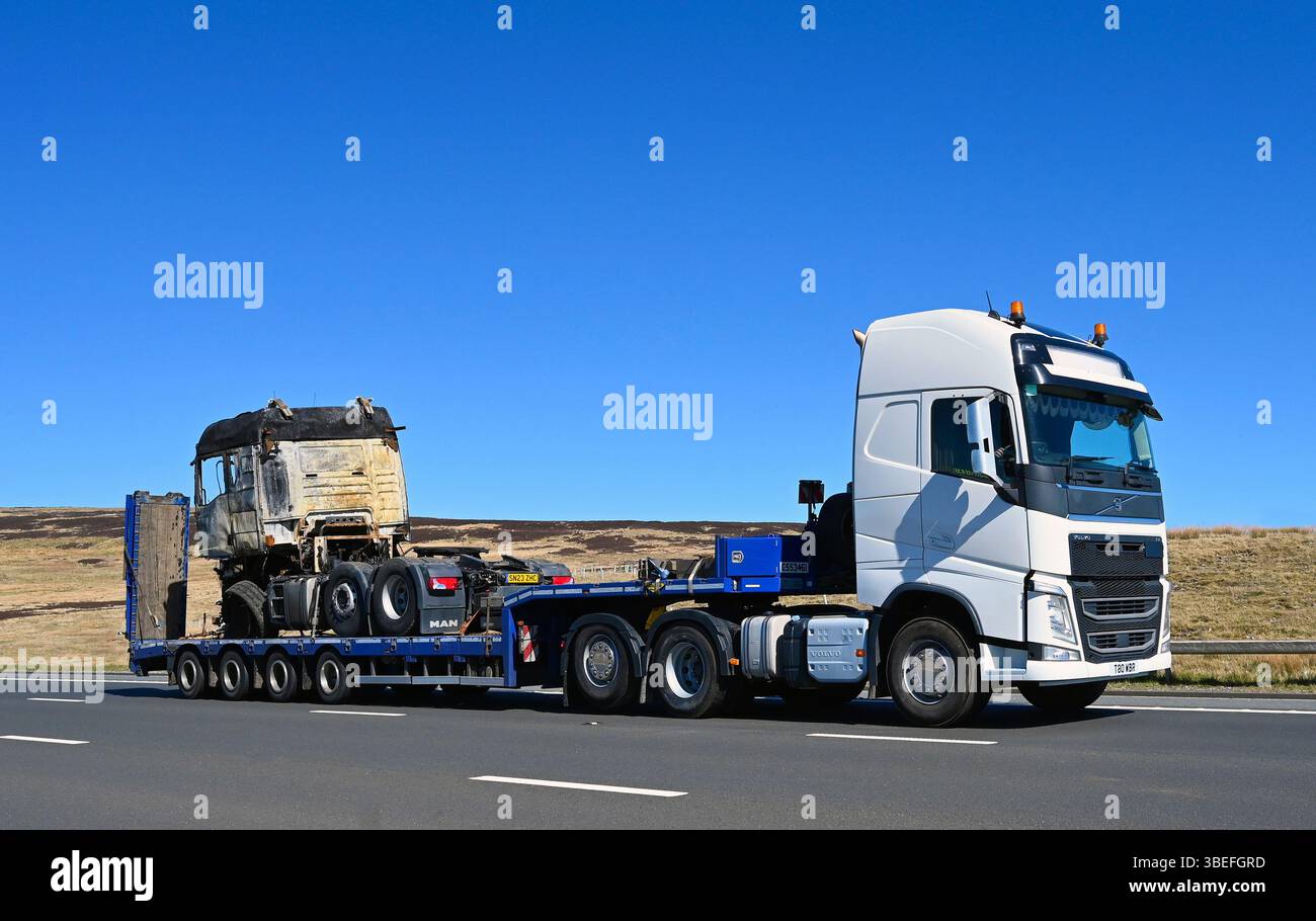Volvo Low-loader HGV carrying wrecked HGV tractor unit, travelling at ...