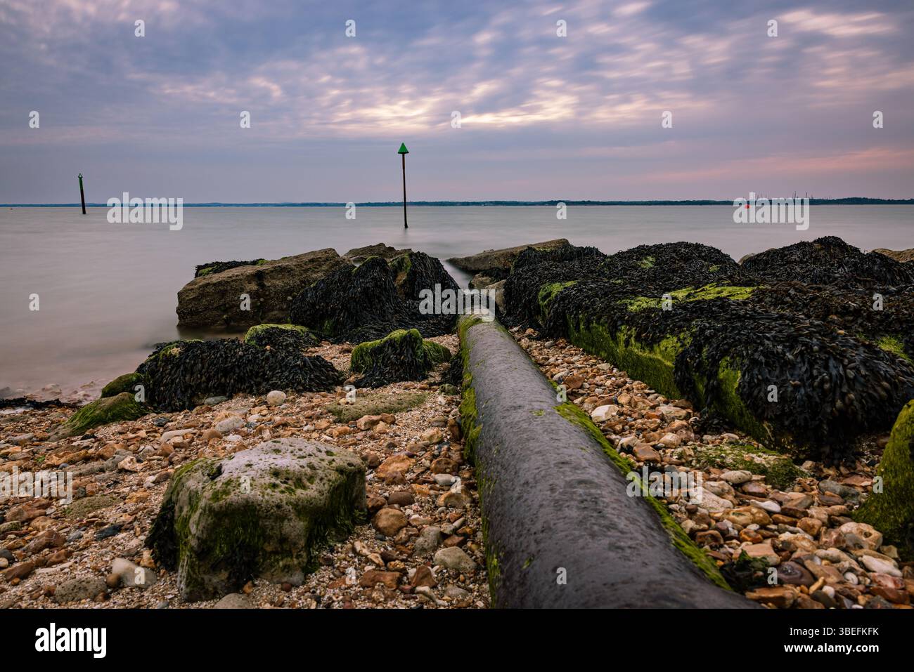 Long exposure of coastal rocks and an algae-covered outflow pipe at low ...