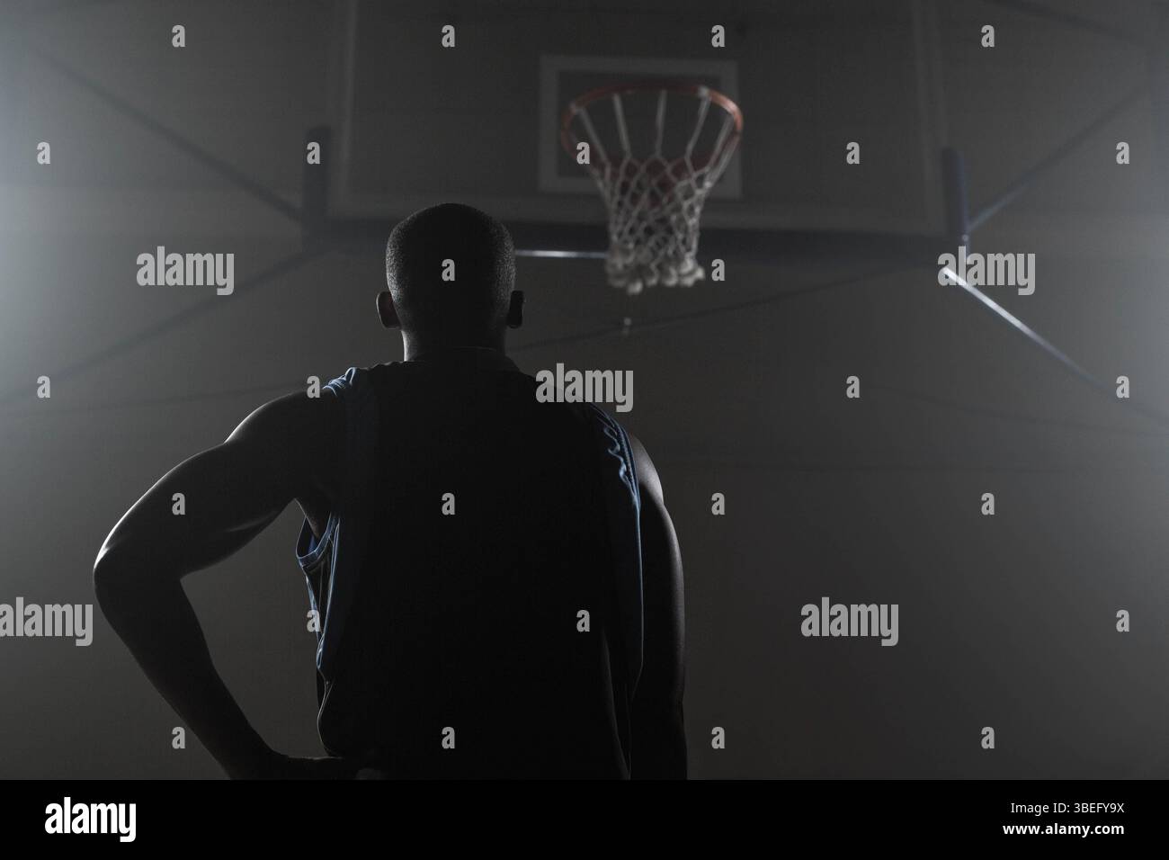 Basketball player standing at free-throw line in gym, looking up at ...
