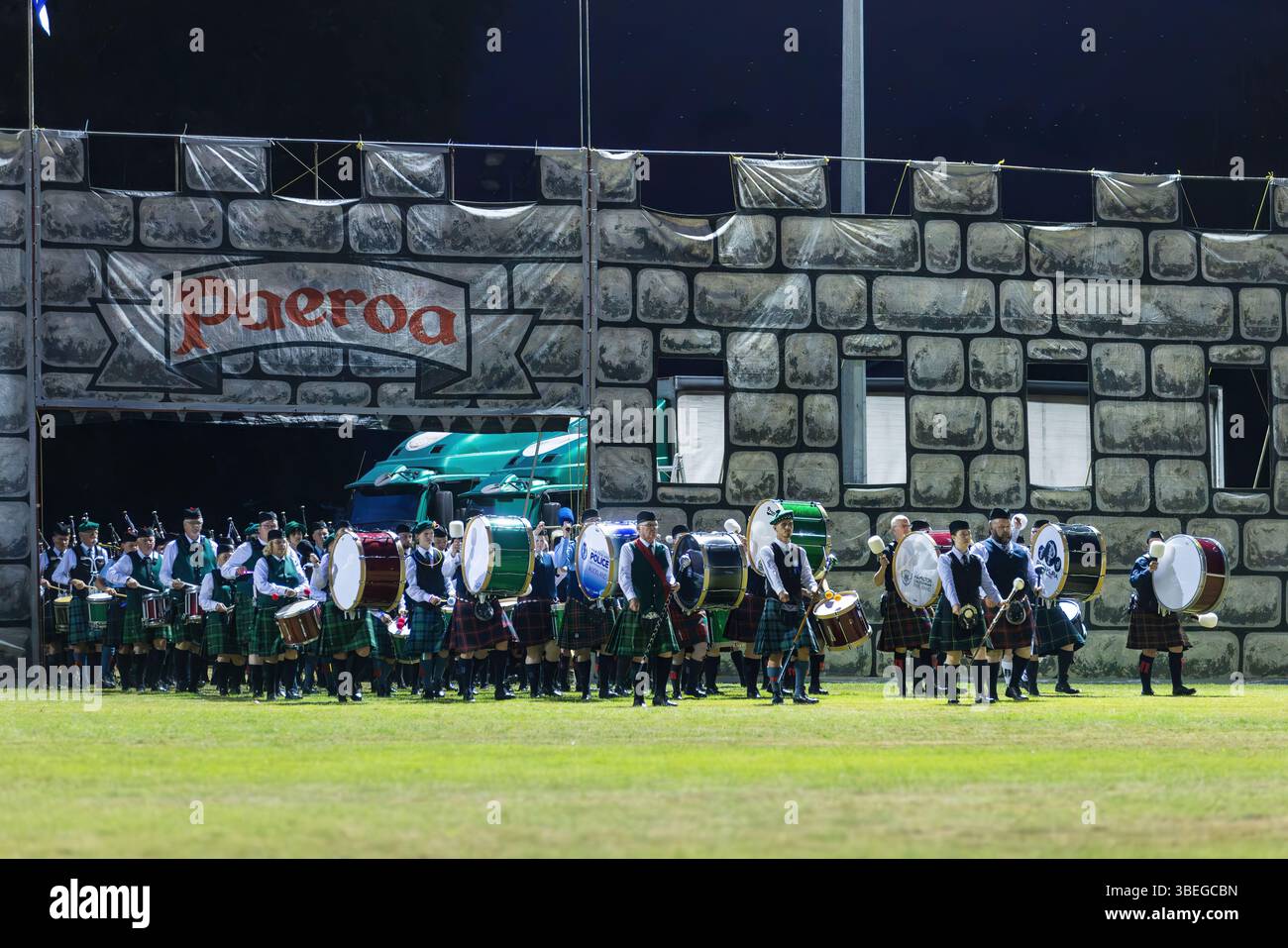 A traditional Scottish pipe and drum band marching at night during the ...