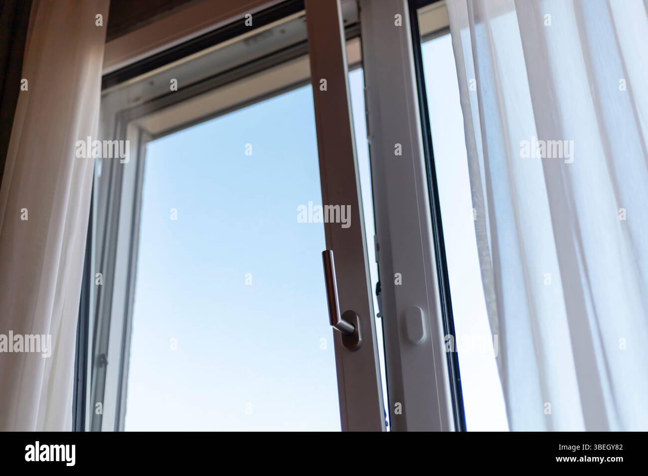 Soft sunlight filters into a room through an open window adorned with ...