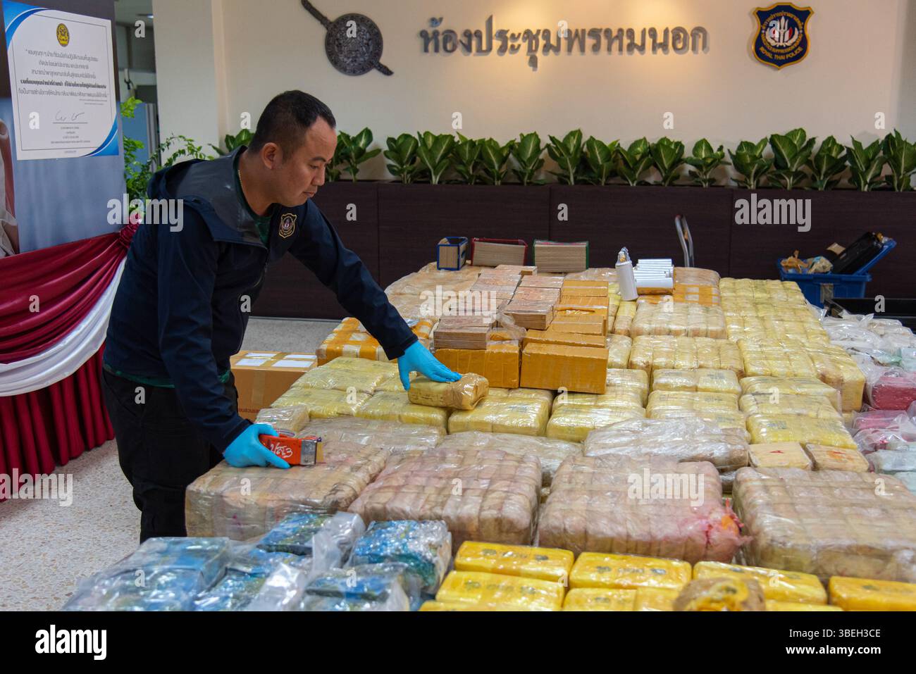 A Thai Narcotics Suppression police officer seen checking the pile of ...