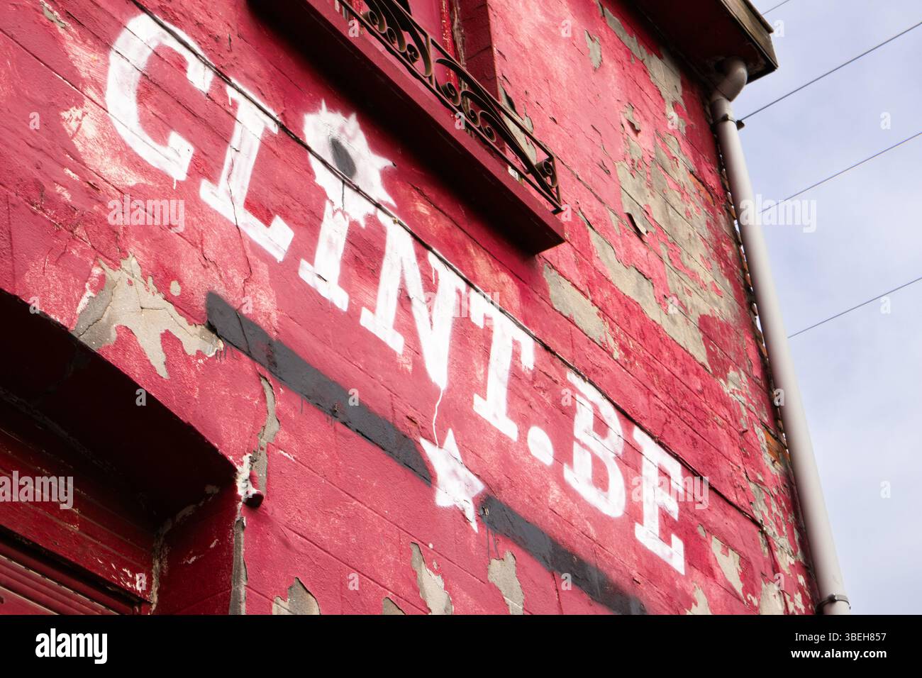 Old red wall with faded lettering and peeling paint in an urban setting ...