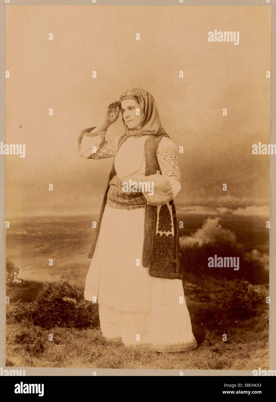 This studio portrait shows a woman dressed in traditional Greek ...
