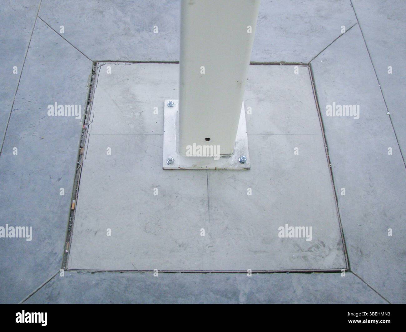 Steel base plate securing metal column to tiled floor Stock Photo - Alamy