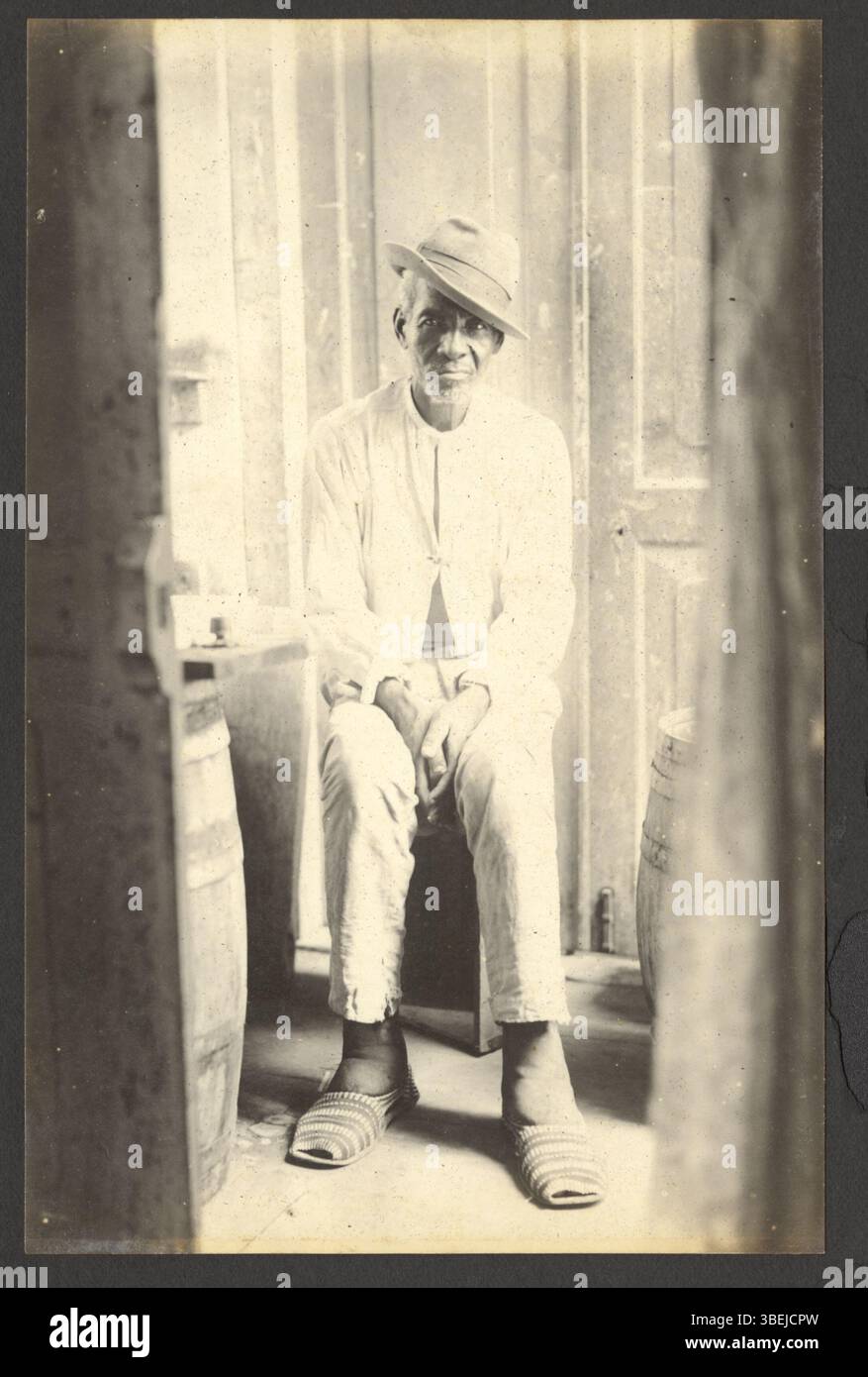 A photograph showing a man sitting by a door opening, taken between ...