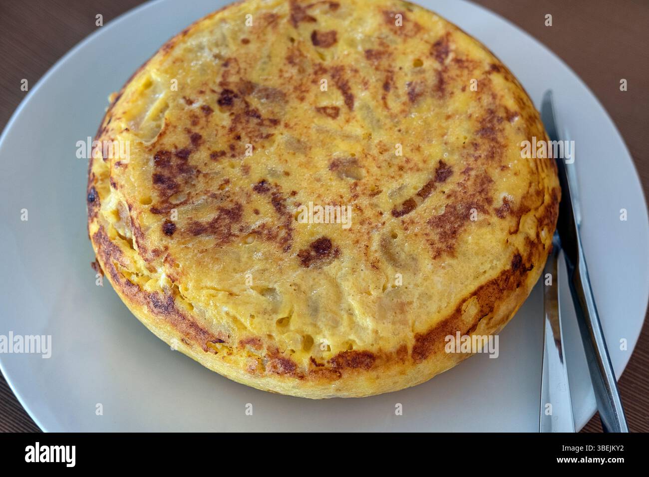Homemade whole tortilla set on a table, golden-brown omelette prepared ...