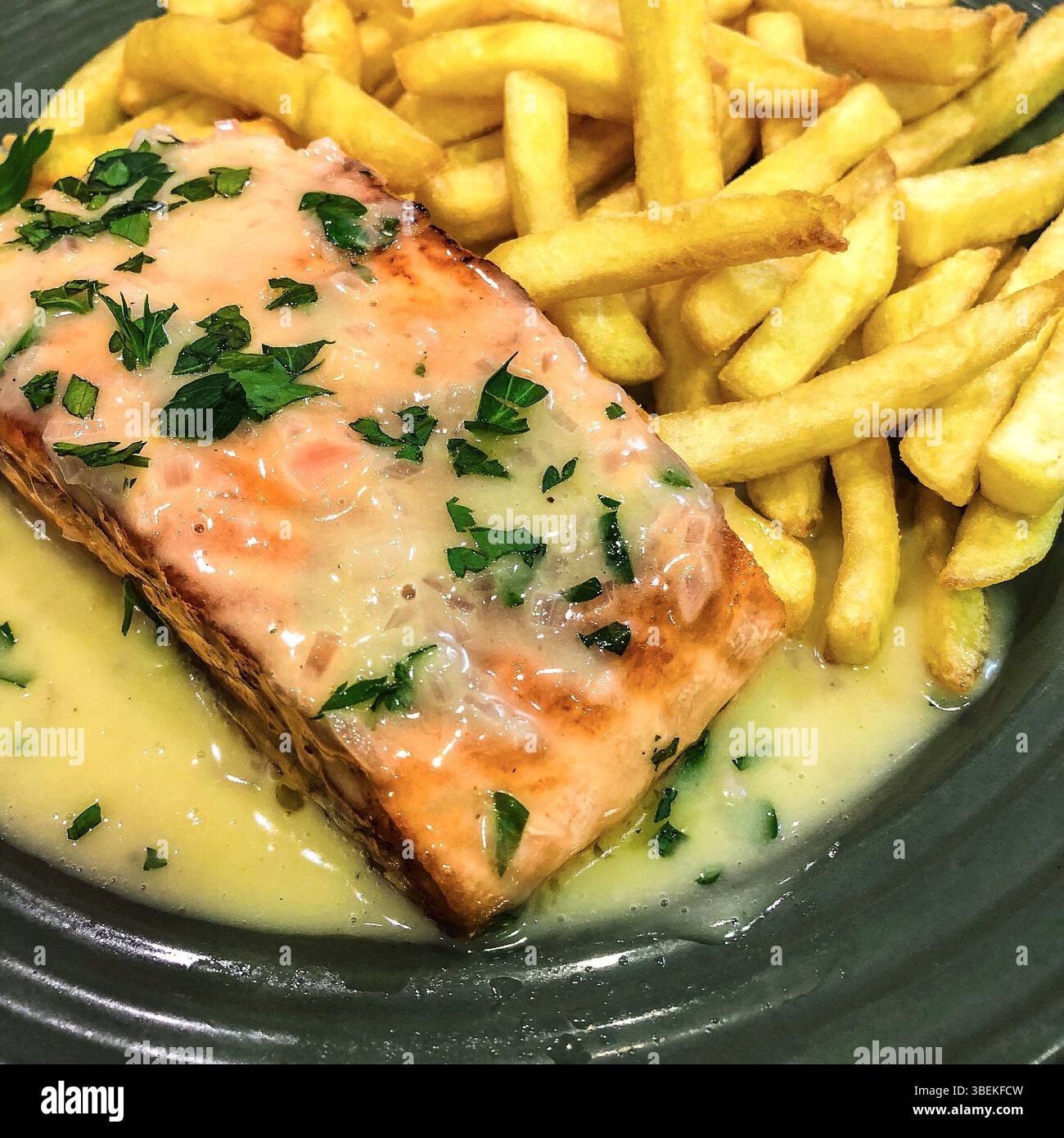 Traditional lunchtime meal of chips, a piece of salmon, a butter sauce ...