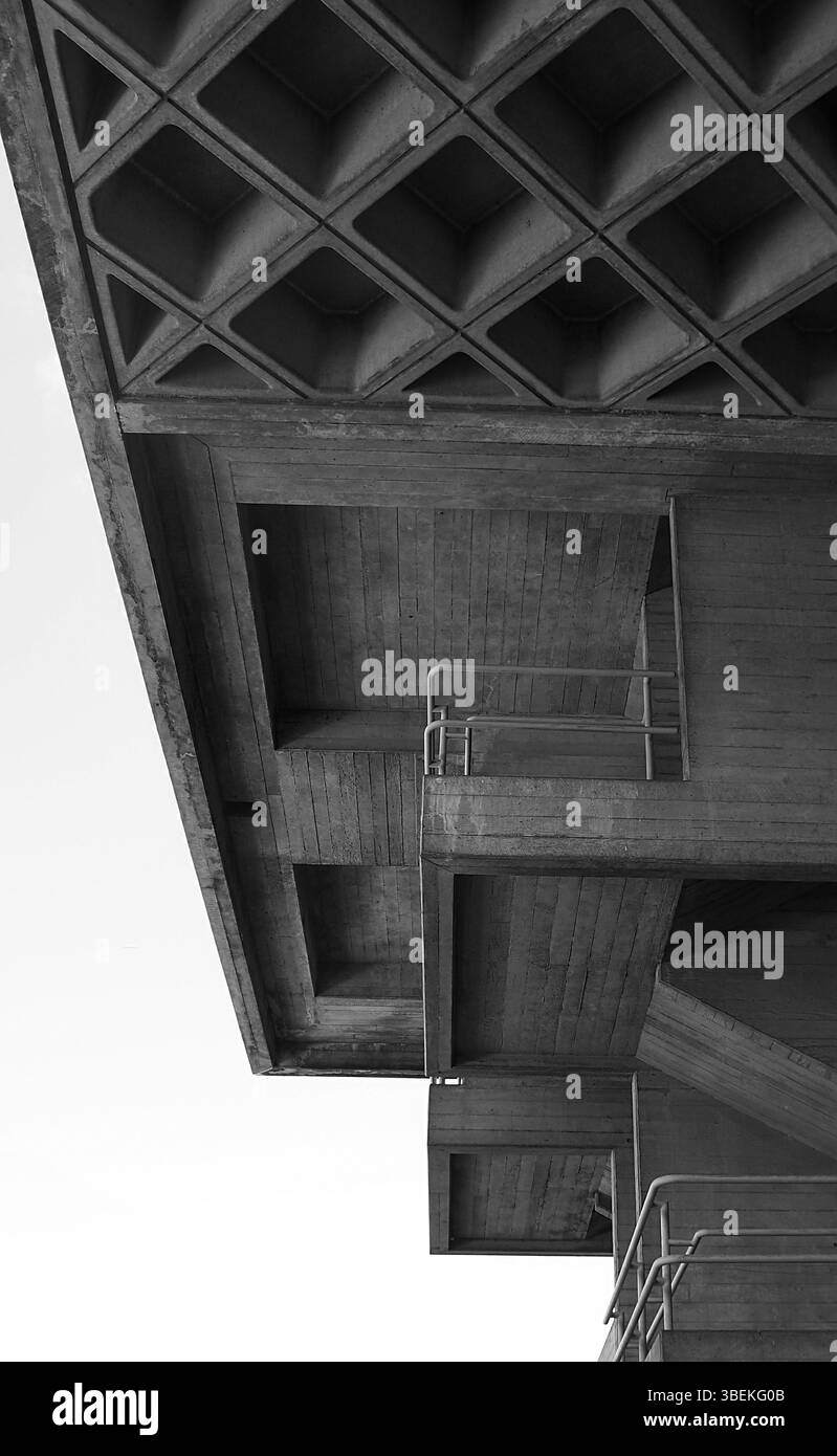 An upward view of a Brutalist architectural structure reveals its raw ...