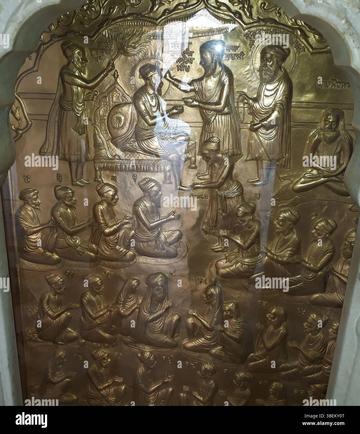 This brass plaque depicts the Gurgadi ceremony of Guru Ram Das, where ...