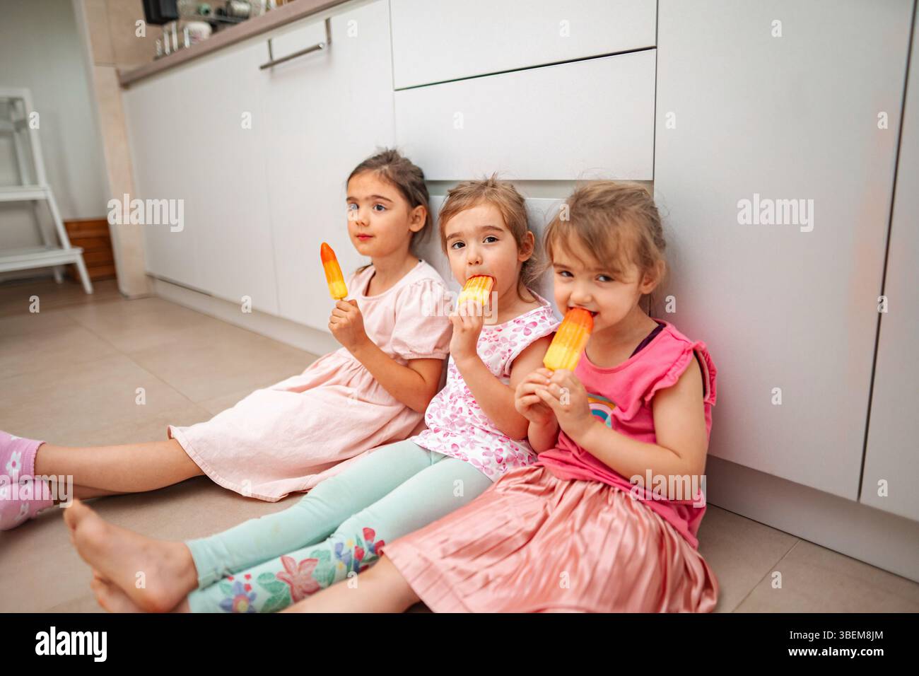 Three joyful girls enjoying colorful ice pops indoors Stock Photo - Alamy