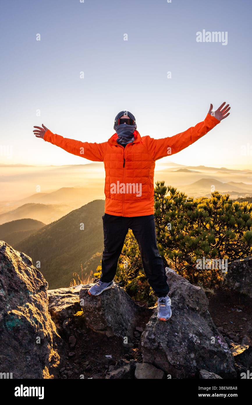 An adventurer wearing a bright orange jacket and face covering stands ...
