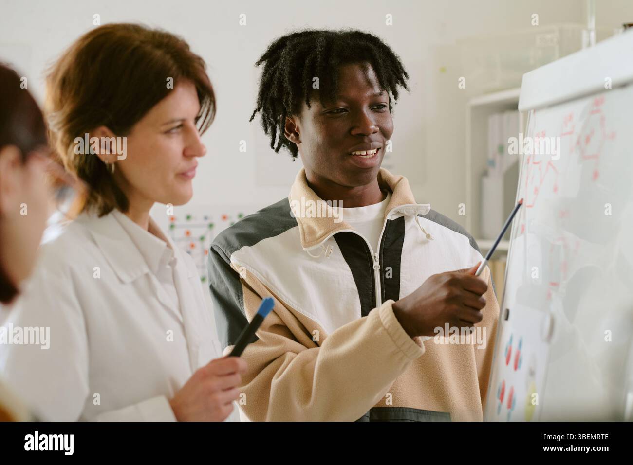 Teacher engaging students with chemistry lesson, holding lab equipment ...