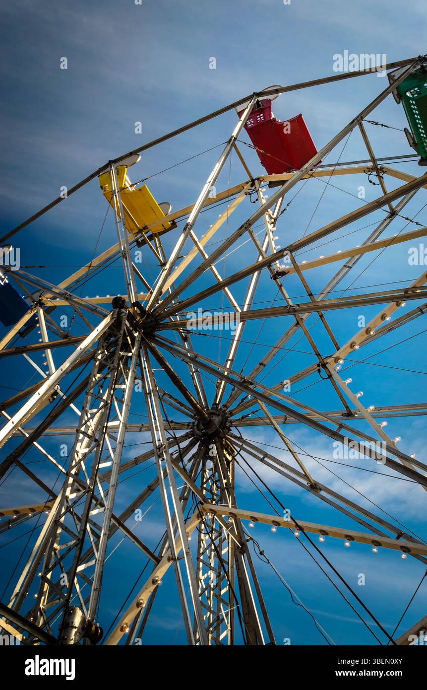 view from below of an antique ferris wheel's primary colored seats and ...