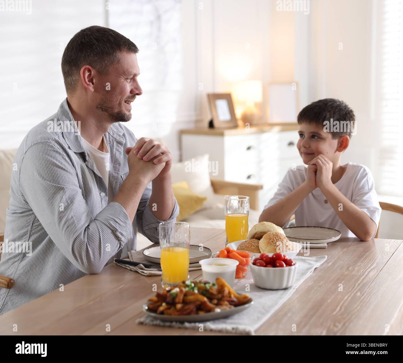 Father and son praying before dinner at table indoors Stock Photo - Alamy