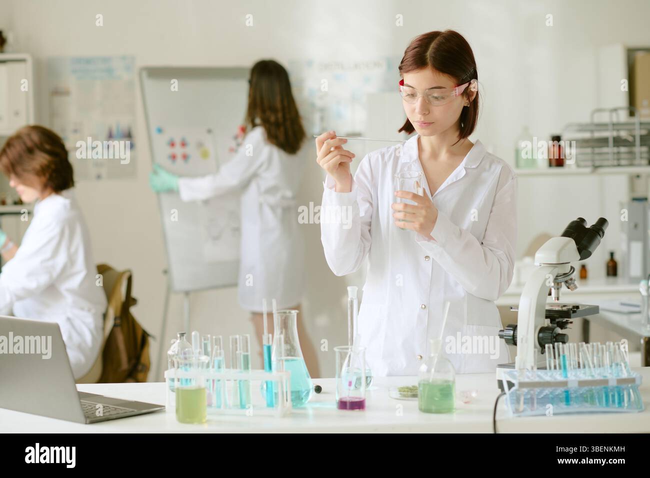 Researchers in white lab coats conducting experiments in chemistry lab ...