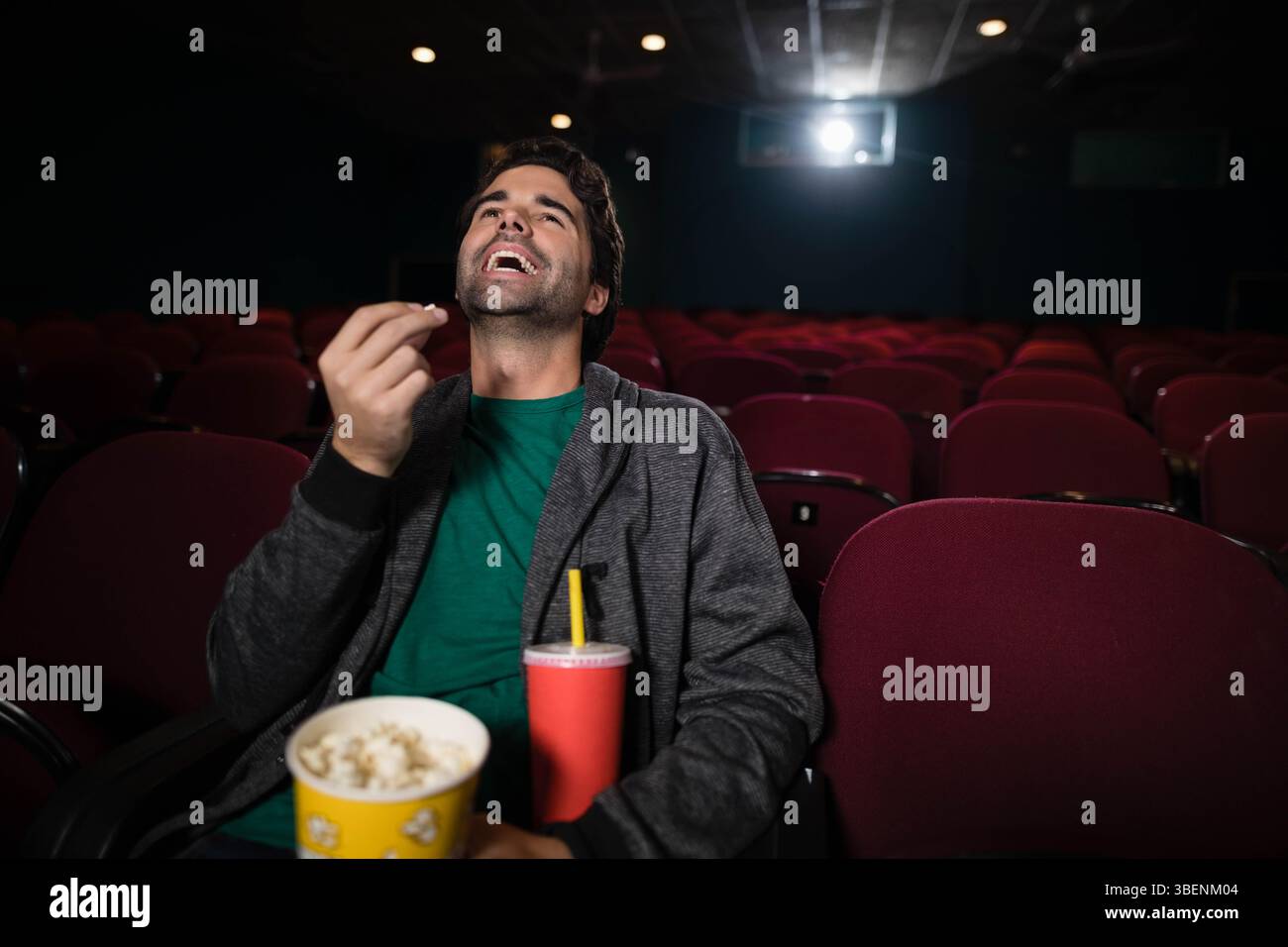 Moviegoer sitting alone in cinema holding yellow popcorn bucket and red ...