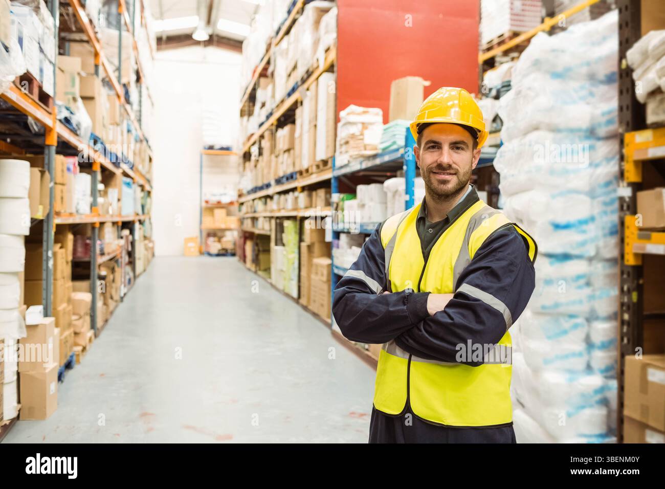Male warehouse worker wearing hard hat in warehouse aisle next to ...