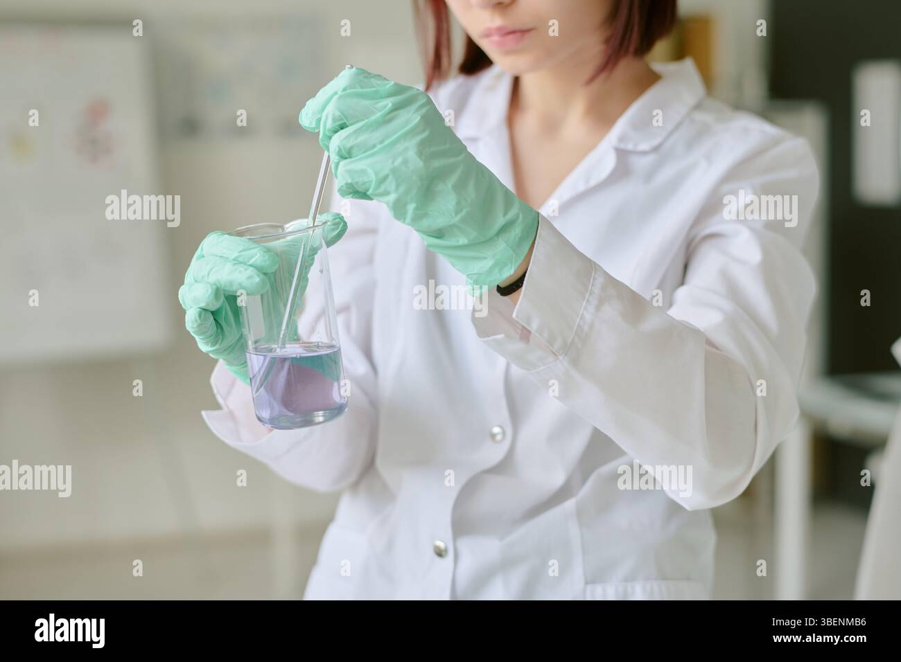 Scientist performing chemical experiment with glove clad hands holding ...