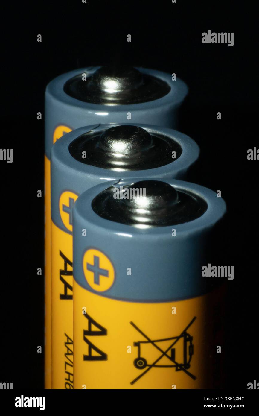 Close-up of AA batteries displaying the positive terminals on a black ...