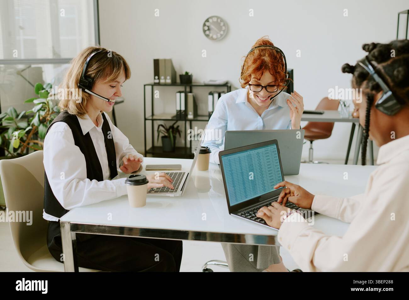 Diverse team working on laptops and engaging in lively discussion in ...
