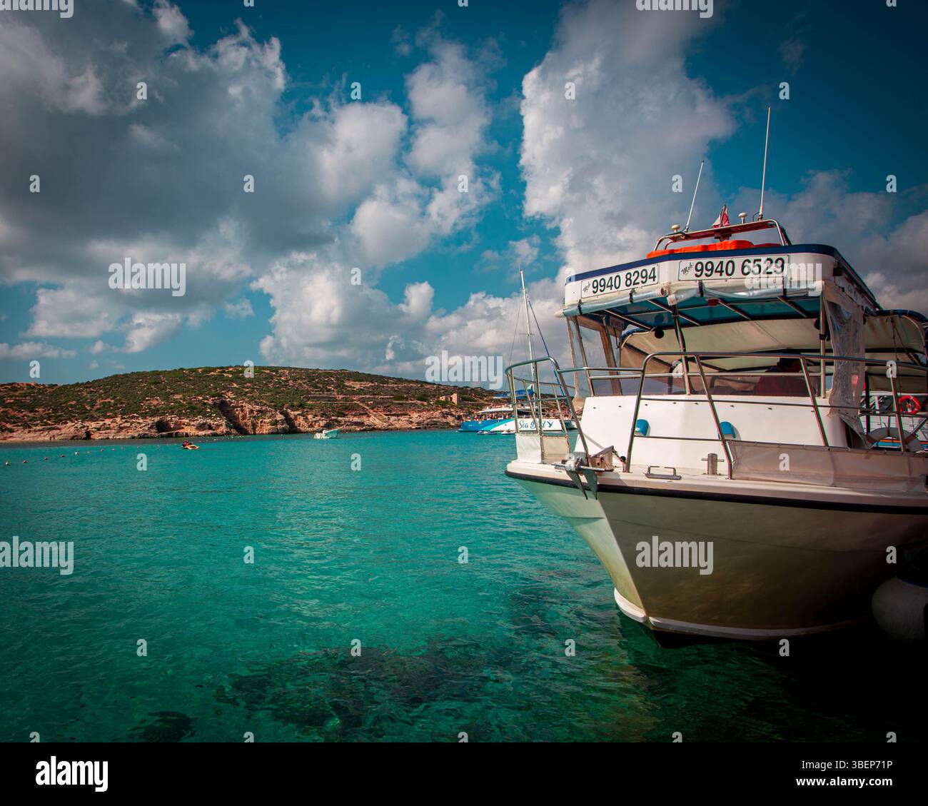 Boats anchored in turquoise waters near rocky limestone coastline of ...