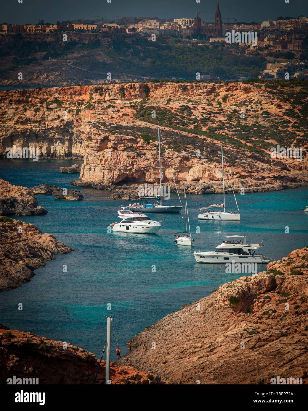 Boats anchored in turquoise waters near rocky limestone coastline of ...