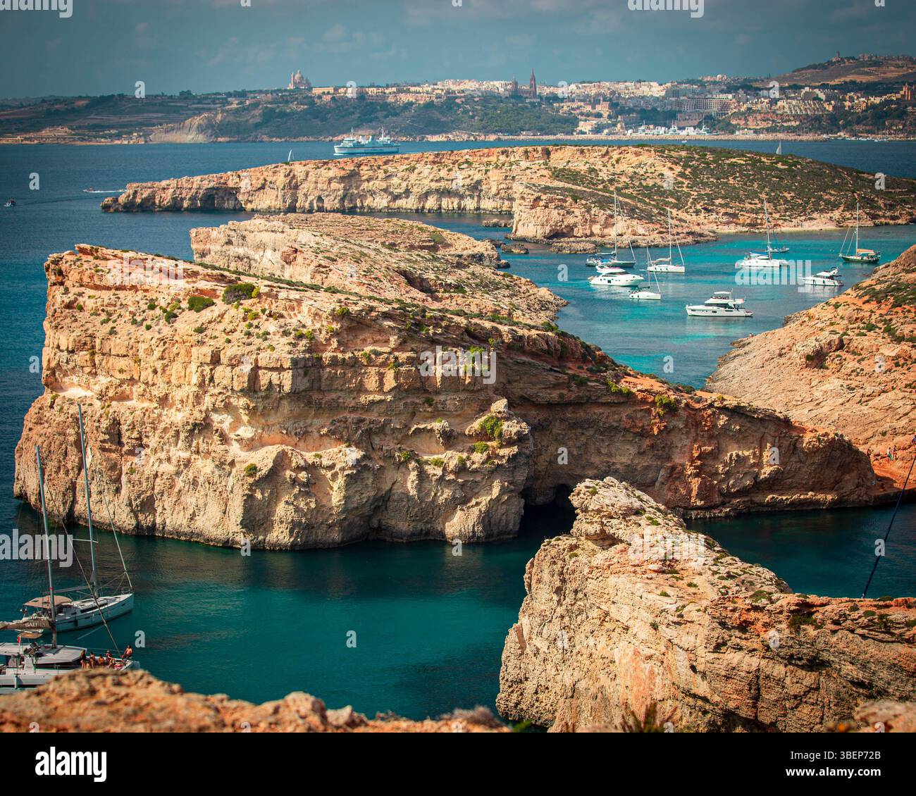 Boats anchored in turquoise waters near rocky limestone coastline of ...