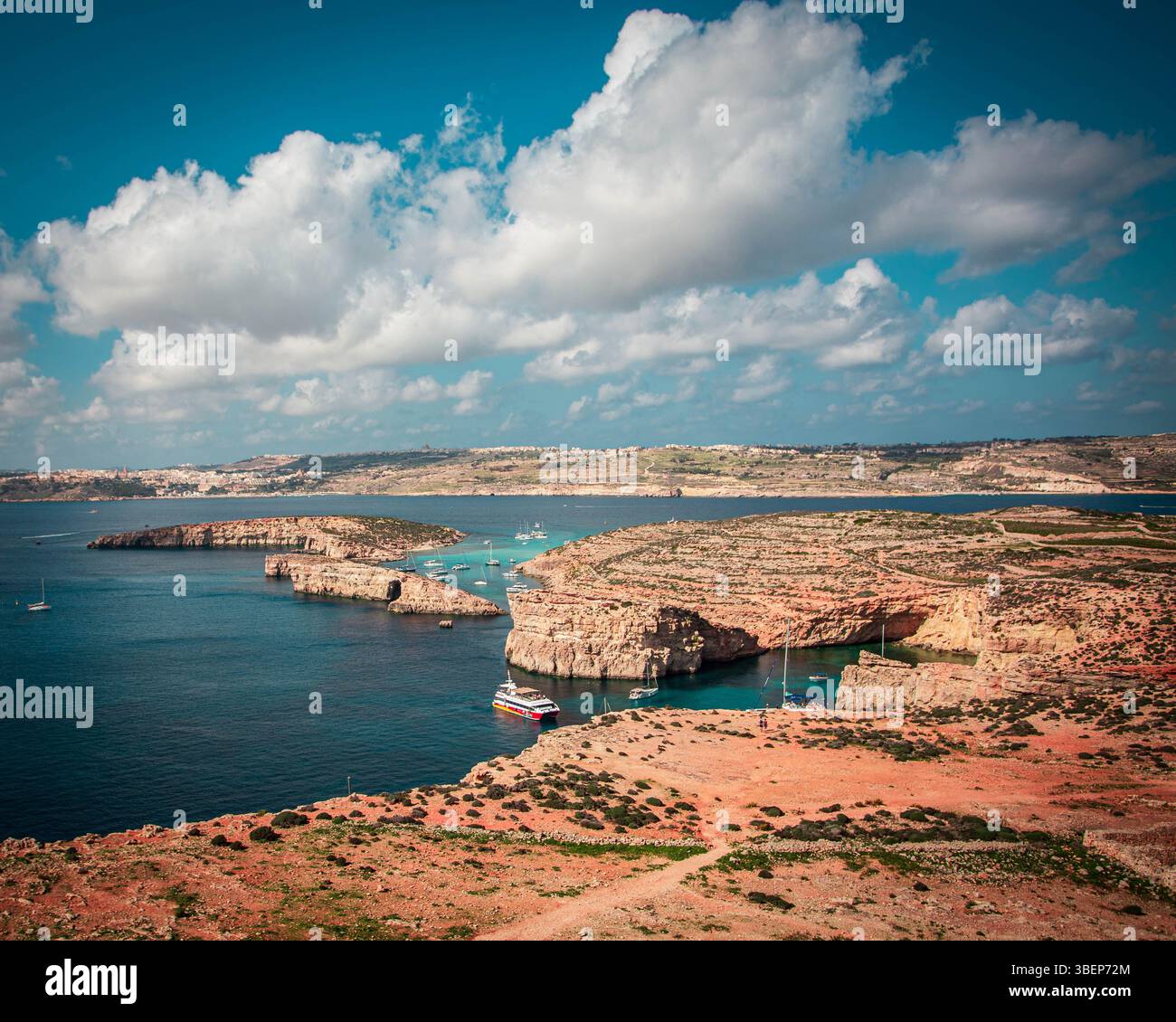 Boats anchored in turquoise waters near rocky limestone coastline of ...