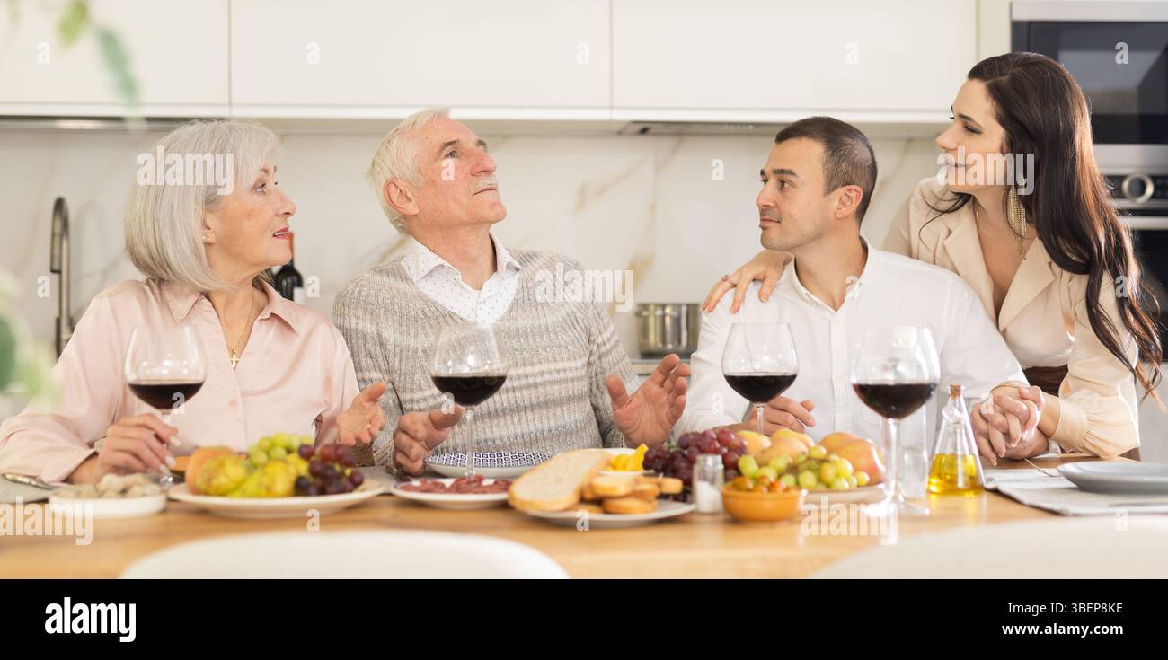 Couple tenderly hold hands and look into each others eyes during family ...