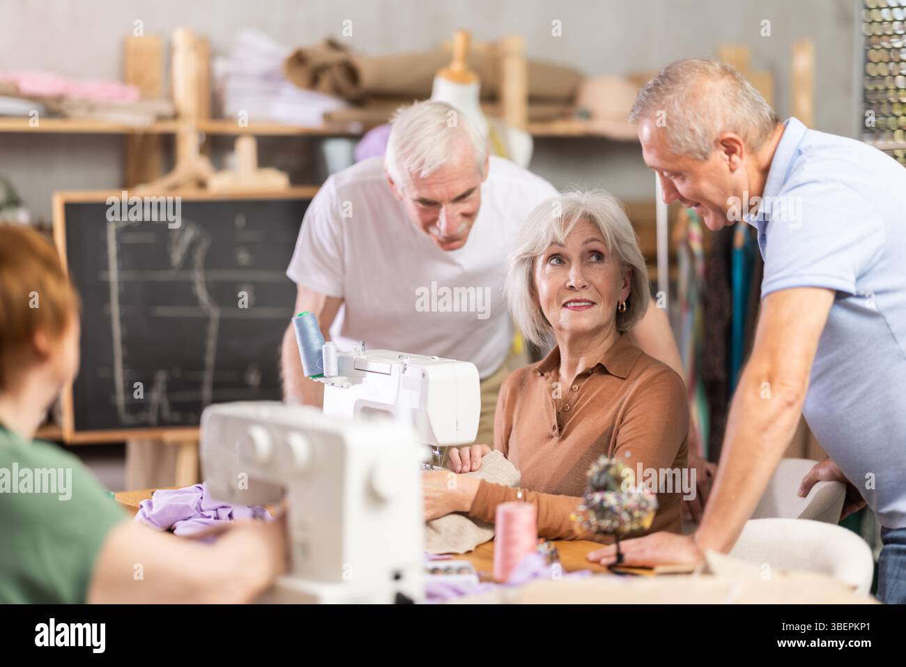 Aged woman stitching at machine during sewing class for seniors Stock ...