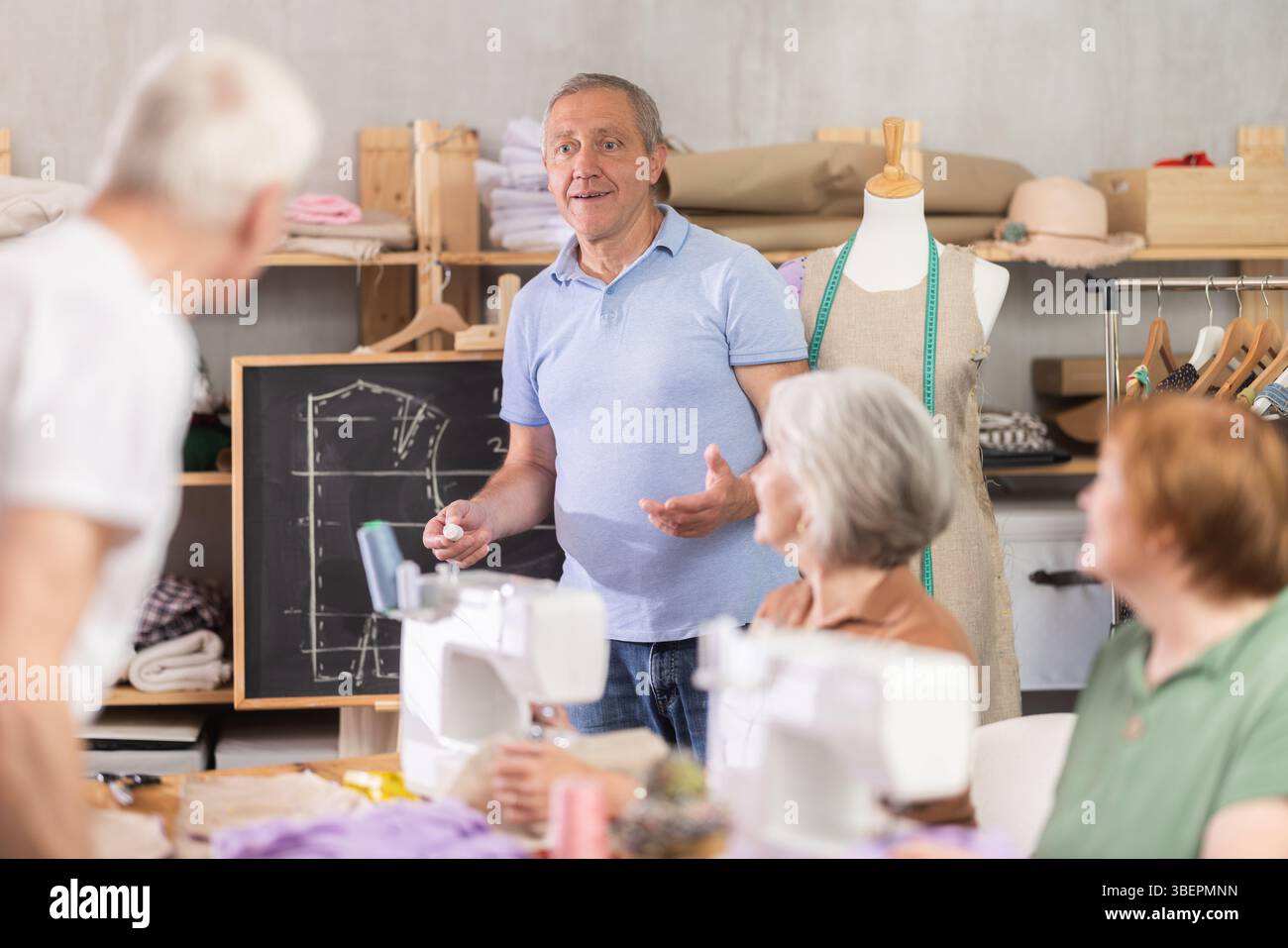 Sewing school senior man teacher conducts lesson for elderly students ...