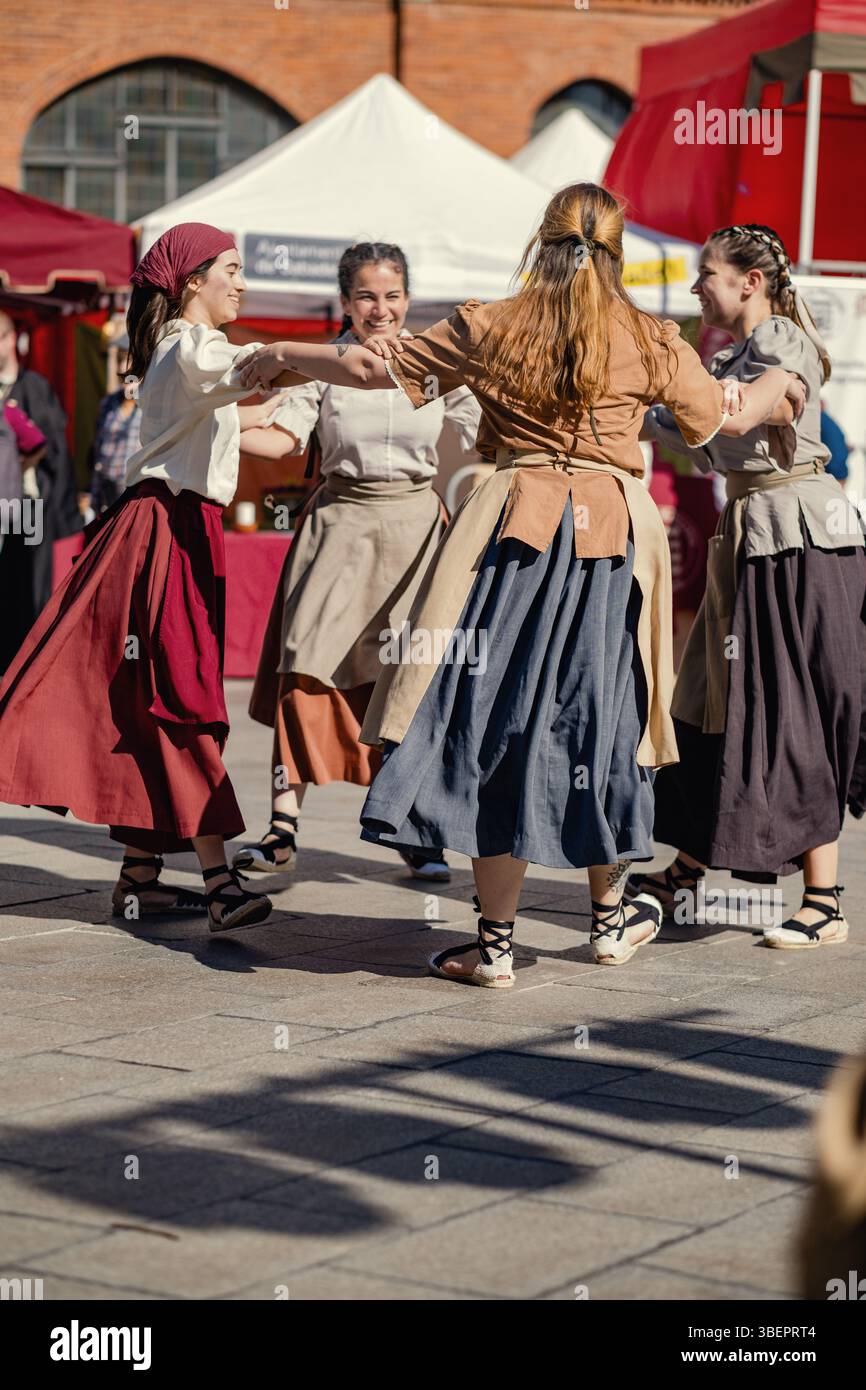 Four young women wearing medieval clothes are holding hands and dancing ...